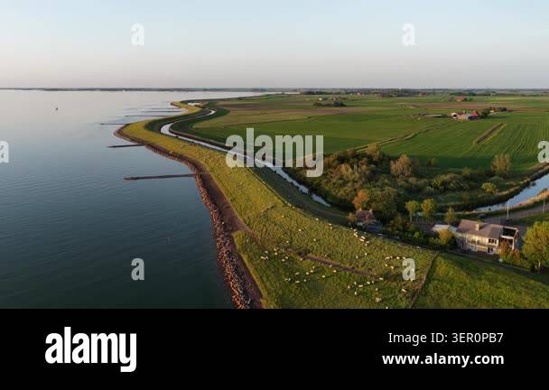 Aerial drone view flying along a typical dutch dike separating the calm ...