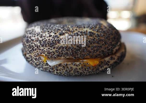 People eat a poppy seed bagel with egg and cheese at a cafe Stock Video ...
