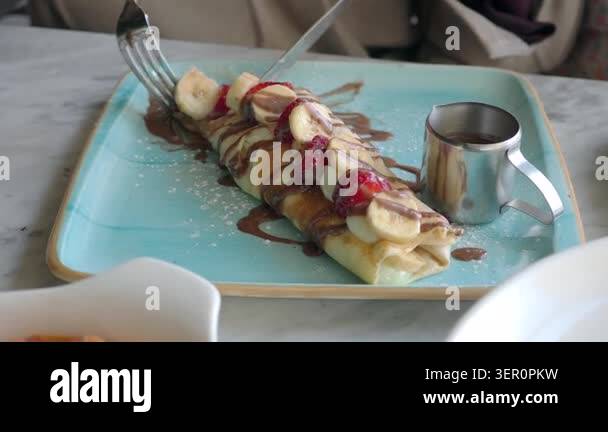 A person eats a dessert crepe topped with fruits and sauce Stock Video ...