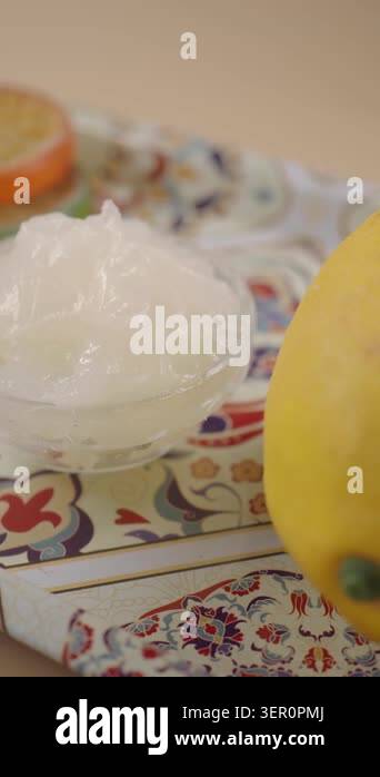 petroleum jelly in a small glass container and lemon on a table Stock ...
