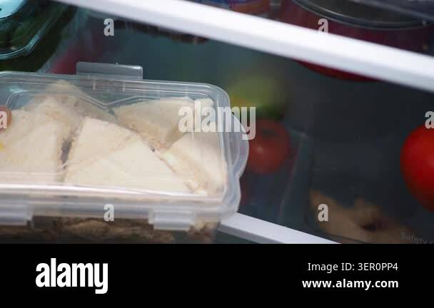 Food items are shown inside a fridge with sandwiches and vegetables ...