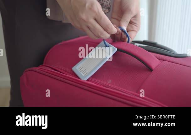 Person Attaching a Luggage Tag to a Red Suitcase Stock Video Footage ...