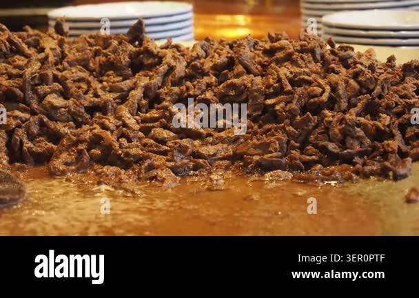 Beef is cooked on a hot grill while people enjoy food around Stock ...