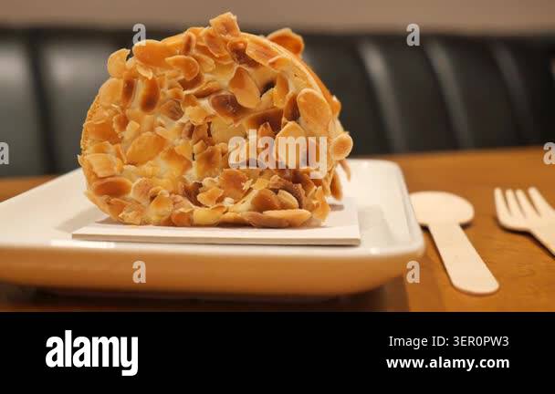 A person eats a dessert with almond pieces at a cafe table Stock Video ...