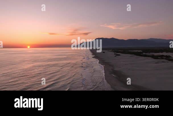 Aerial flight along an endless sandy beach as gentle waves wash ashore ...