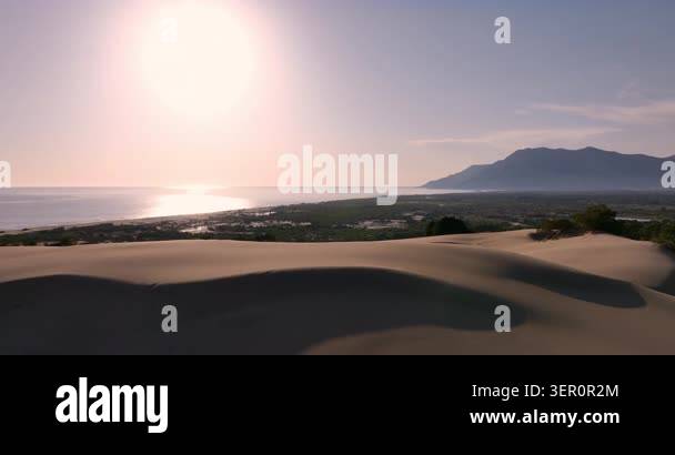 Drone glides above rolling sand dunes revealing the coastline sea and ...