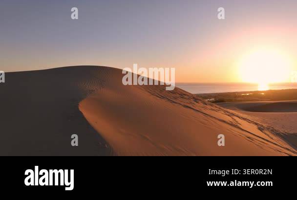 Drone glides above sandy dunes vegetation and rocky coastline as the ...