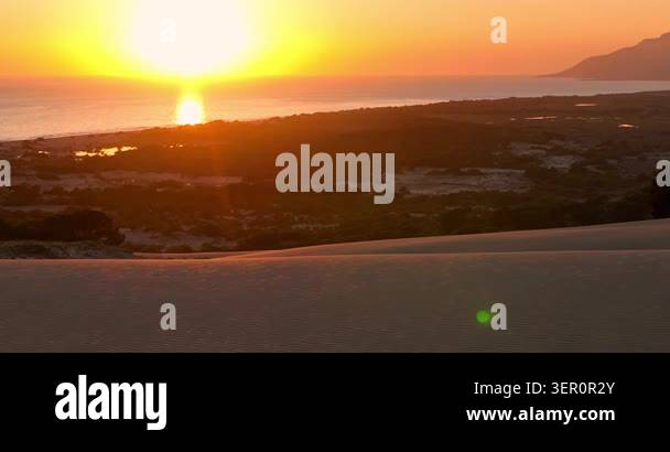 Drone glides above sandy dunes vegetation and rocky coastline as the ...