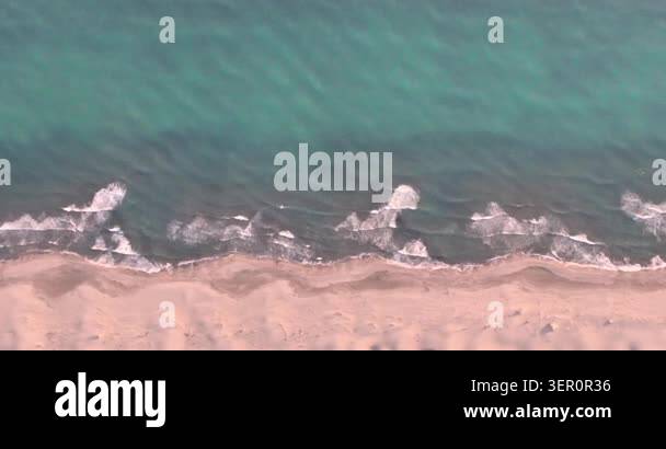 Overhead drone shot captures gentle waves breaking and washing onto a ...