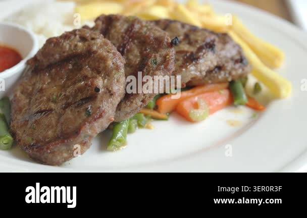 This shows grilled meat slices served with veggies and fries Stock ...