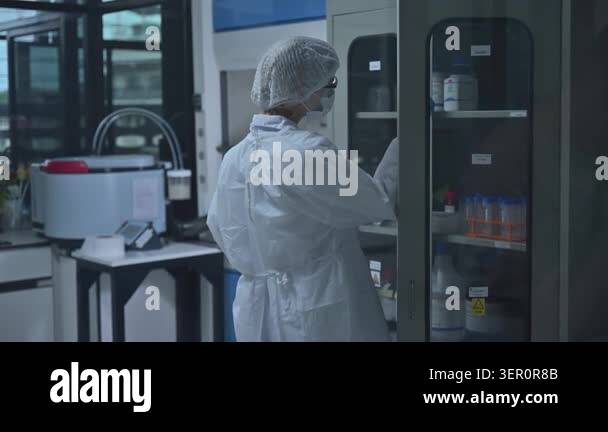 Professional researcher wearing protective cleanroom suit take chemical ...