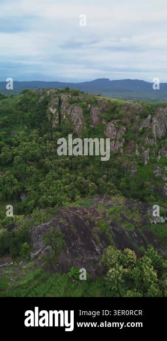 4K aerial footage of a beautiful ancient rocky hill surrounded by trees ...
