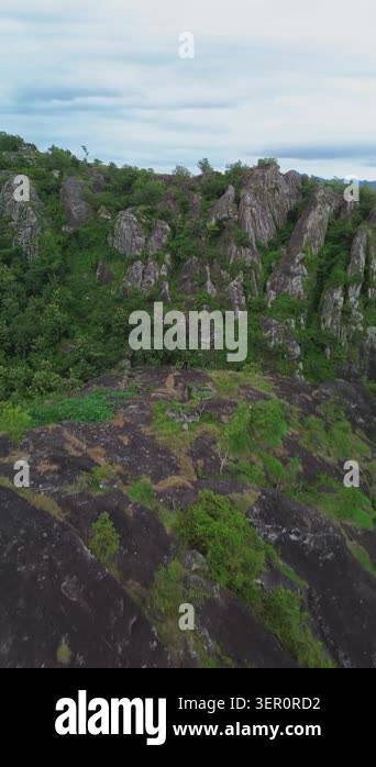 4K aerial footage of a beautiful ancient rocky hill surrounded by trees ...