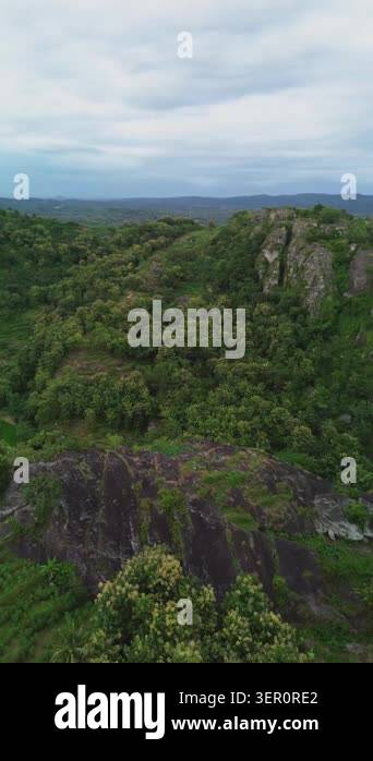 4K aerial footage of a beautiful ancient rocky hill surrounded by trees ...