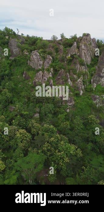 4K aerial footage of a beautiful ancient rocky hill surrounded by trees ...