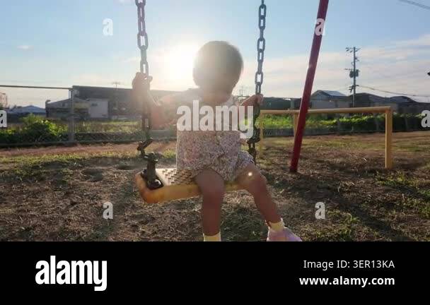 Cute Happy Toddler Enjoying a Swing Ride at a Mini Park During Golden ...