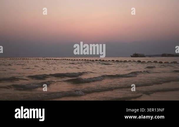 Beautiful sunset over the tropical sea with gentle waves crashing on ...