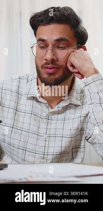 Exhausted Indian businessman reviewing documents reports while using ...