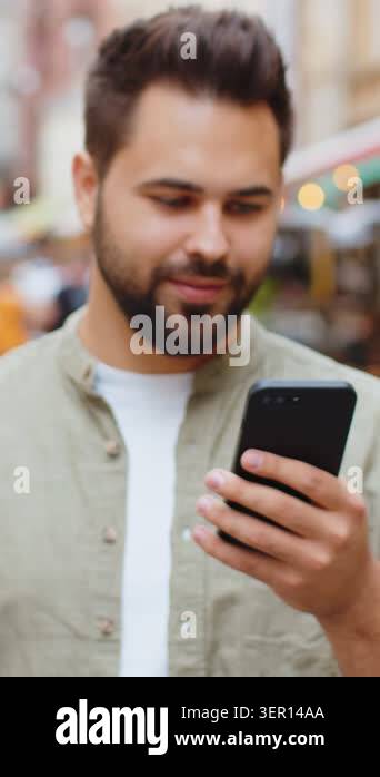 Smiling bearded man using smartphone typing text messages browsing ...