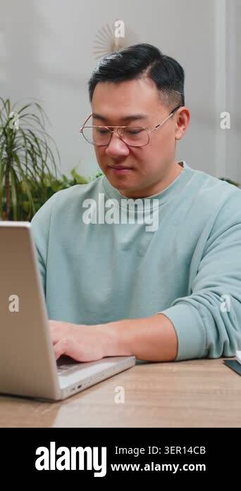 Asian man sitting on sofa closing laptop pc after finishing work in ...