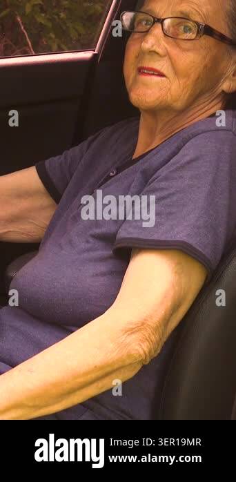 Old woman driving a car in the countryside, road trip concept. Portrait ...