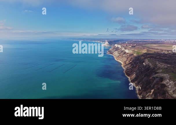 The scene shows a vast area of blue water meeting cliffs along a ...