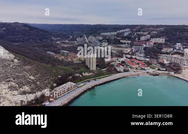 Aerial view shows a small coastal town with buildings near the shore ...
