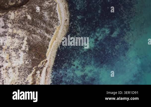The view shows a coastline meeting the ocean, featuring rocky areas and ...
