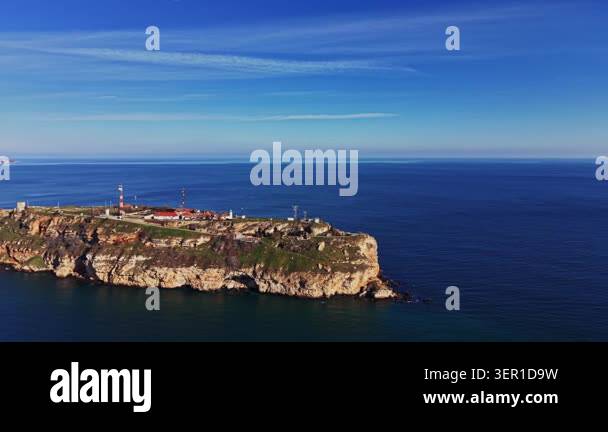 The image shows a coastline with cliffs and a small building on top ...