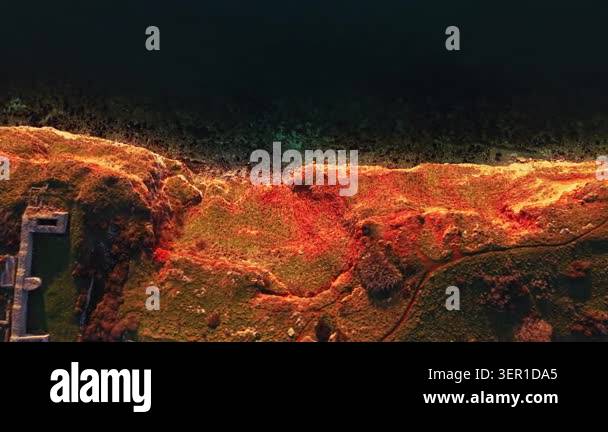 Aerial view shows a rocky shore at sunrise with bright colors glowing ...