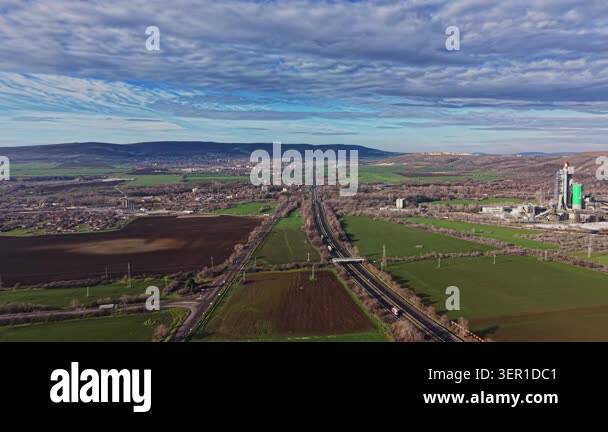 A view of a large area with green fields and brown soil. Mountains are ...