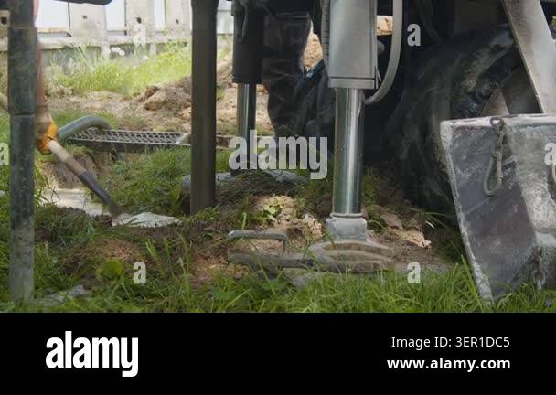 Workers operate a drilling machine to create a water well on a site ...
