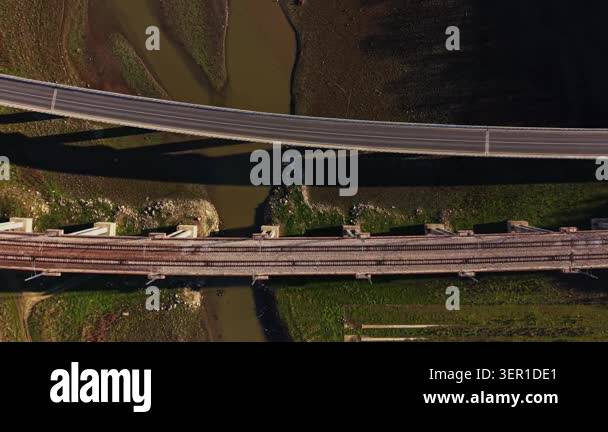 Two roads run above a river and grassy land. The view is from above ...