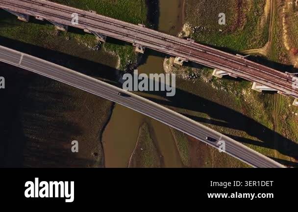 Two roads and railway tracks cross over a river. The view shows ...