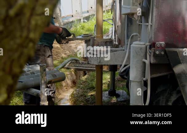 Workers drill into the ground to access water for a well at a ...