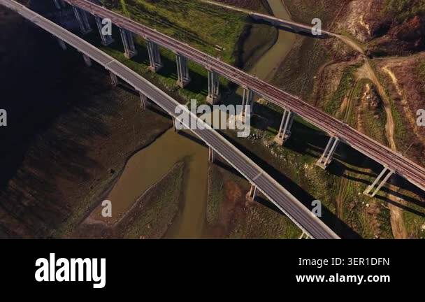 Two bridges connect over a river in a rural area. One bridge is for ...