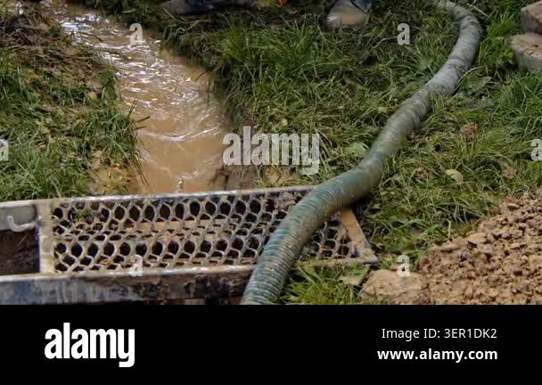 Workers are drilling a water well in a muddy area, using equipment to ...