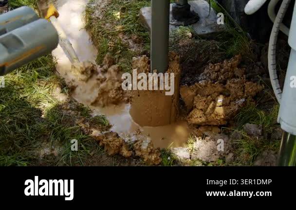 Workers are drilling into the ground to reach water while mud and soil ...