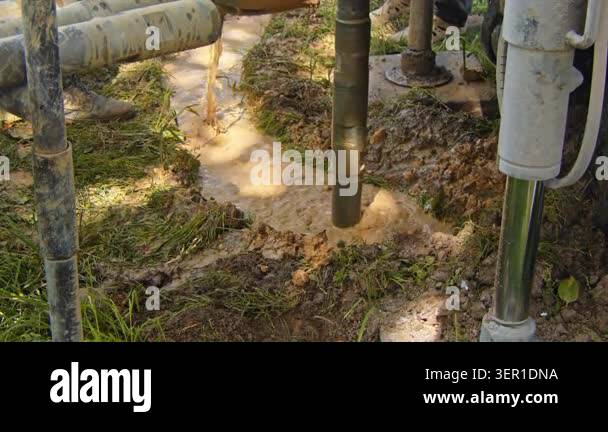 Workers drill into the ground to reach water during a well installation ...