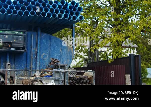 Workers prepare drilling equipment for a water well. The site shows ...