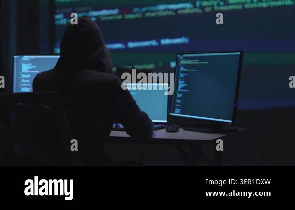A hacker works intently, showcasing multiple screens filled with code ...