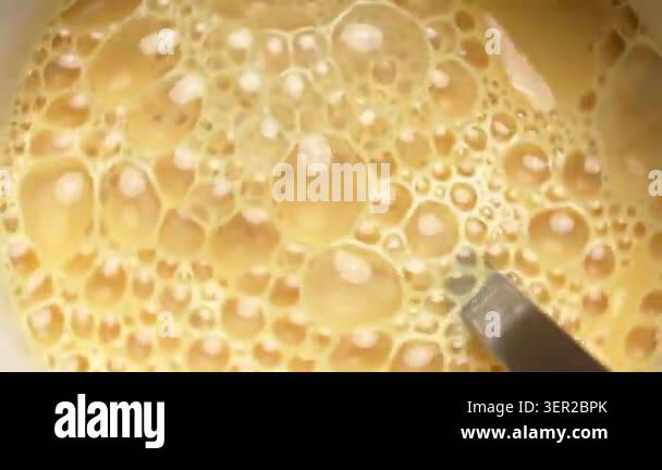 Golden milk foam bubbles moving in circular motion inside mug ...