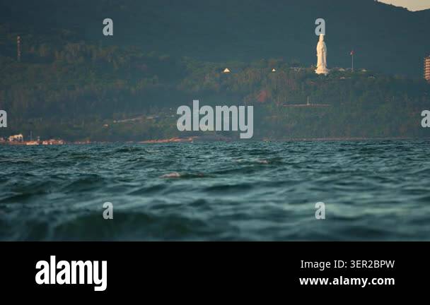 Lady Buddha statue and Linh Ung Pagoda above coastline with sea waves ...