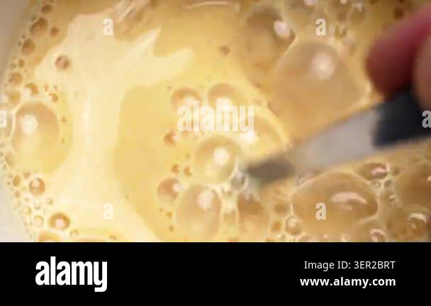 Turmeric powder being stirred into plant based rice milk with metal ...
