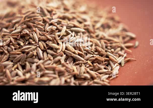 Macro shot of a heap of whole dried cumin seeds resting on a rustic ...