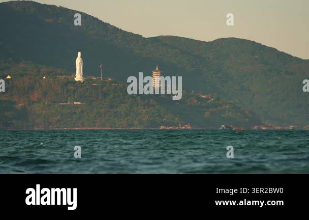 Lady Buddha statue and Linh Ung Pagoda above coastline with sea waves ...