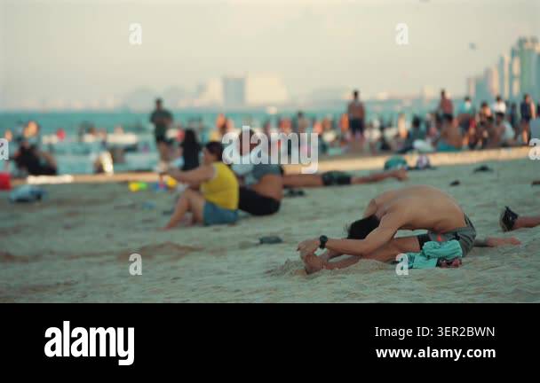 Man stretching on sandy beach with people relaxing along tropical ...