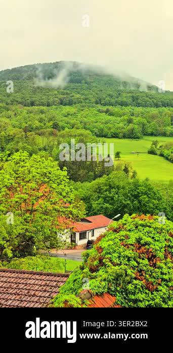 Mountain with fresh green grass in spring. Clouds over and on the ...