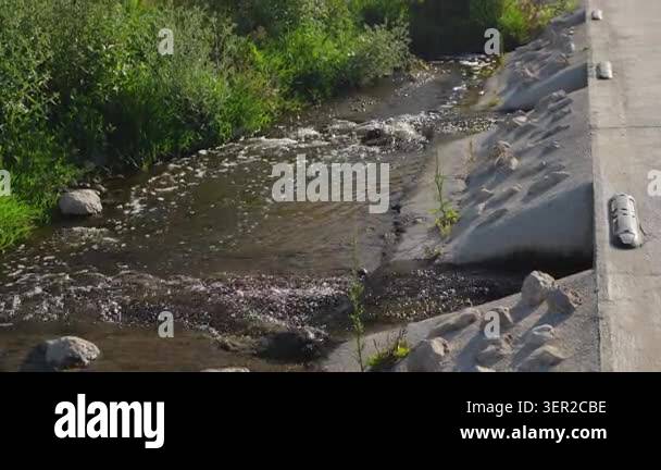 Small stream flowing through concrete drainage channel with green ...
