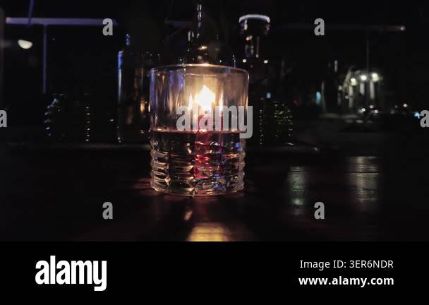 Nighttime slow motion fixed close-up high contrast video of a bar table ...